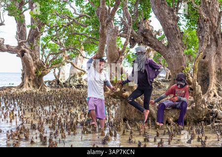 Filipino fishermen resting beside an old growth mangrove tree in Isla ...