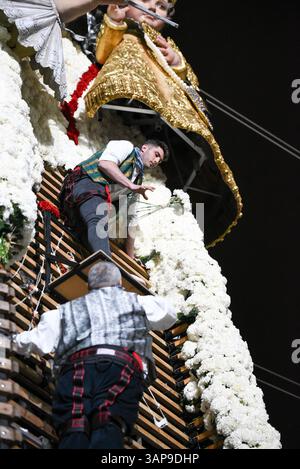 Men in traditional costume climbed on a giant wooden structure ...