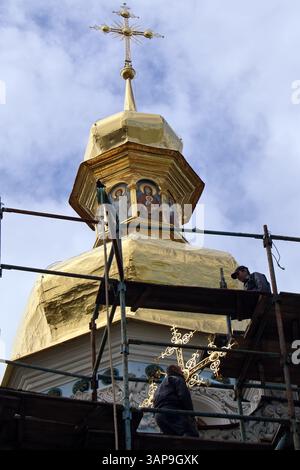 Workers install a cross on top of a dome of the 12th-century Gate ...