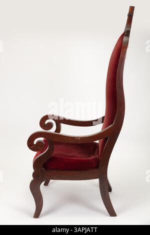 A high-backed priest's chair featuring a red velvet upholstered seat ...