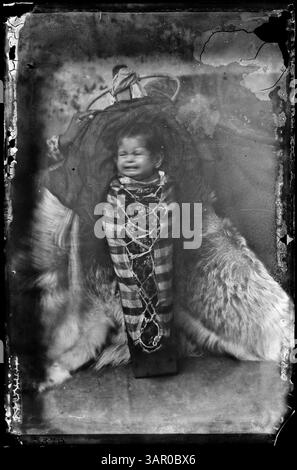 Photograph of tribal infants in cradles. The image reflects the early ...