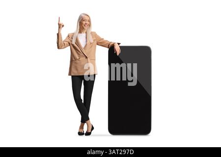 Tall woman pointing at a big mobile phone isolated on white background ...