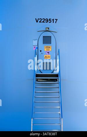 A wind power plant with modern wind turbines and trees under a blue sky ...