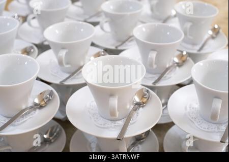 Many empty tea cups on saucers with teaspoons Stock Photo - Alamy
