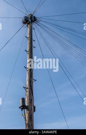 Wooden pole with modern telecoms equipment and multiple wires forming a ...