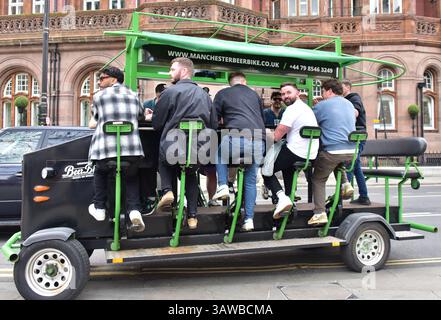 A group of men pedal a Manchester Beer party bike through central ...