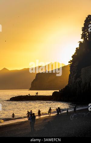 Silhouettes of beachgoers on Free Castelletto Beach at sunset. Spiaggia ...