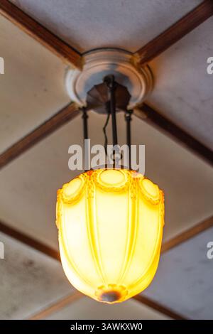 A vintage chandelier hangs from a ceiling with marble archways and ...