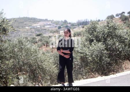 A Palestinian child walks along a street surrounded by buildings ...