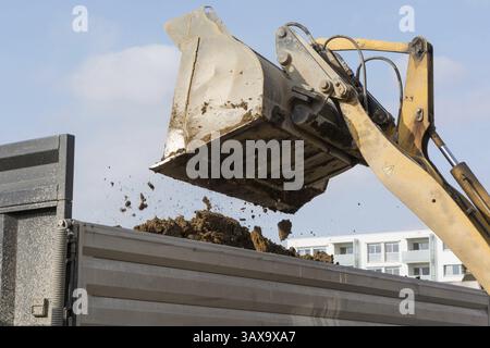 Shovel loader tips soil from construction site into low-loader Stock ...