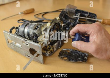 Plumber Repairs Broken Jigsaw With Screwdriver Stock Photo - Alamy