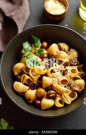 Pipe rigate pasta with roasted mushrooms in black ceramic bowl over ...