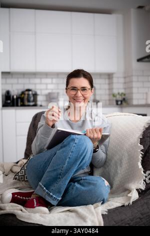 Happy young student reading notes in copybook and recording voice ...