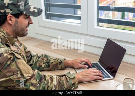 Soldier sitting near laptop on couch and talking on phone Stock Photo ...