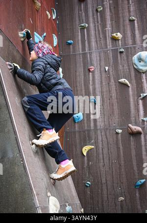 Girl practicing on a climbing wall, demonstrating strength, agility ...