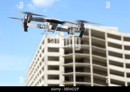 Drone with camera flying near unfinished building. Unmanned aerial ...