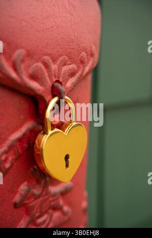 A romantic heart padlock locked onto a bridge railing symbolizes ...