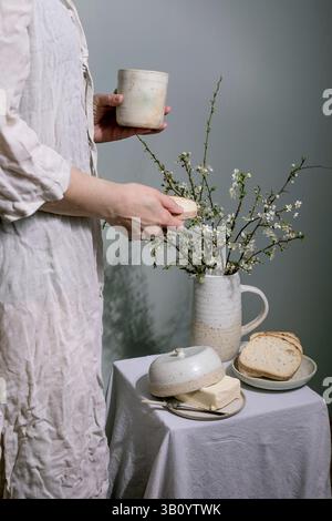 A person holds a white ceramic cup in one hand and a sucrose cube in ...