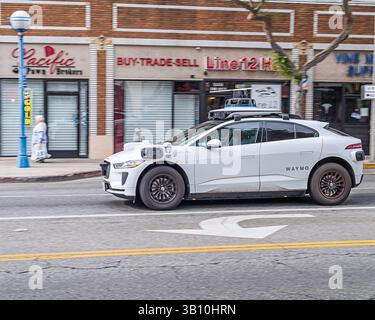 Self-driving Waymo vehicle at city intersection in front of Uber ...