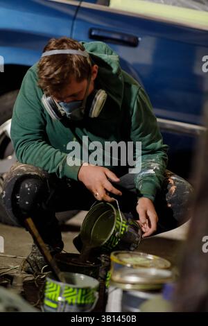 A man crouched on the ground in front of a colorful shophouse and ...