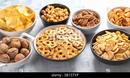 Different kinds of snacks, chips, nuts, popcorn and cookies on a grey ...