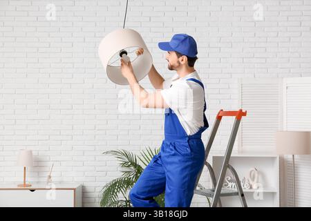 Happy male electrician changing light bulb in floor lamp at home Stock ...