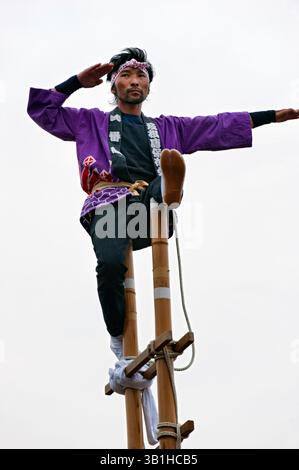 Traditional Japanese fireman performing stunts atop a bamboo ladder ...