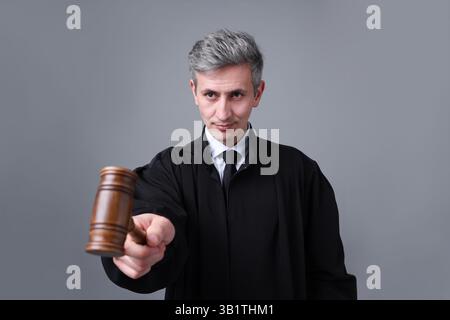 Portrait of judge with mallet on grey background Stock Photo - Alamy