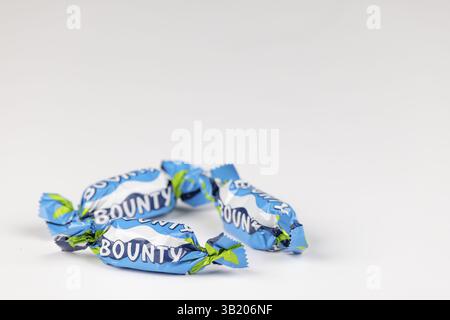 Three Bounty, small chocolate bars on half a coconut on a white ...