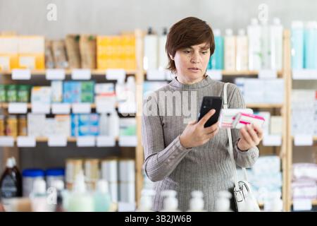 Woman scanning barcode on paracetamol boxes with phone at pharmacy ...