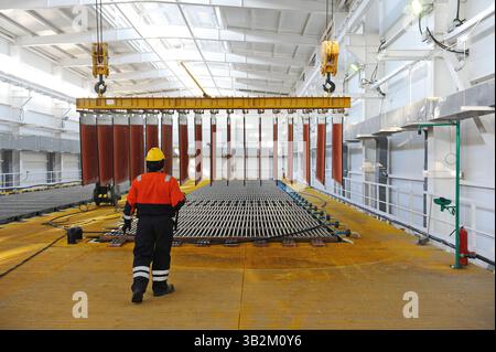 A worker washes plates with cathode copper at an industrial plant Stock ...