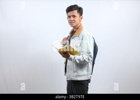 student wearing denim jacket carrying bag and reading book isolated on ...