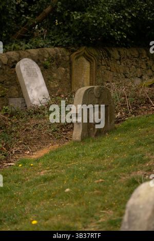 Old stone gravestone partially covered by moss, in a quiet cemetery ...
