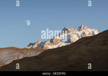 Moon rising above snow covered mountain range in the Austrian alps ...