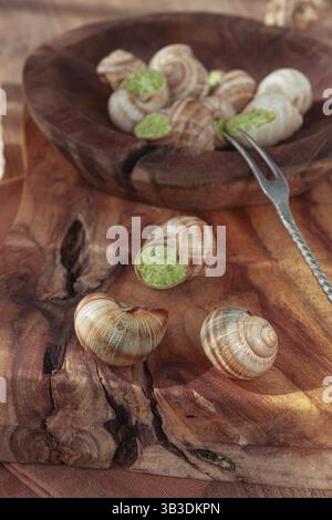 Snails cooked with herb oil on a wooden plate, served with white wine ...