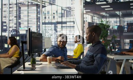 Happy coworker in wheelchair bumping fists with programmer testing ...