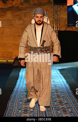 A Kurdish teenager is seen in traditional dress in front of the ...