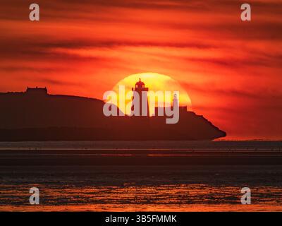 Sunrise aligned with Baily and Poolbeg Lighthouses from Sandymount ...