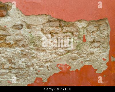 Weathered cracked plaster wall with exposed old stone masonry texture ...