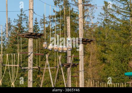 A ropes course stands in a clearing, surrounded by forest. outdoor ...