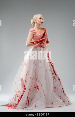 Bride in a blood-stained gown posing elegantly in a studio setting ...