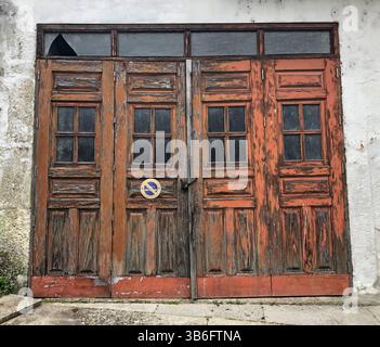 Worn out facade with a wooden gate and a creeper plant hanging from the ...