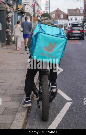 London UK 4 May 2025. A Deliveroo rider making deliveries on Wimbledon ...