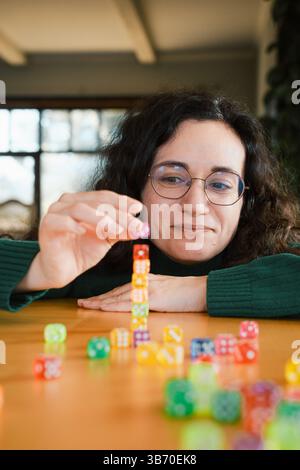 Woman player at her 40s stacking colorful dice during table game night ...