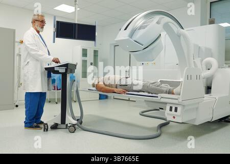 Male patient undergoing X-ray examination using tilting radiographic ...