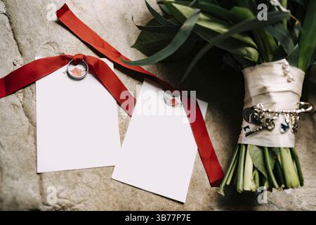 Wedding rings on a stone, a bouquet of pink flowers Stock Photo - Alamy