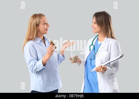 Female homeopathic doctor and mature woman with remedy on light ...