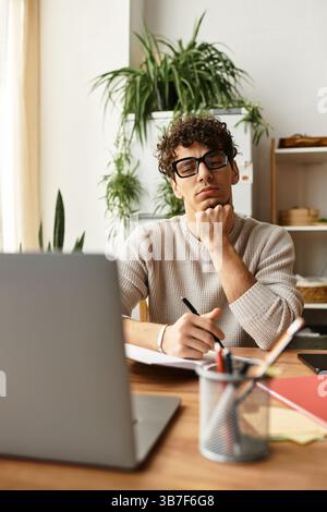 Thoughtful young man writes in his notebook at home, surrounded by a ...