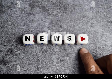 Male hand presses the play button with the news on wooden cubes ...