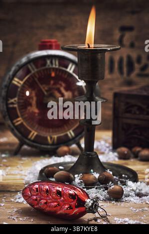 Burning candle in an old brass candlestick and carnival masks on an old ...